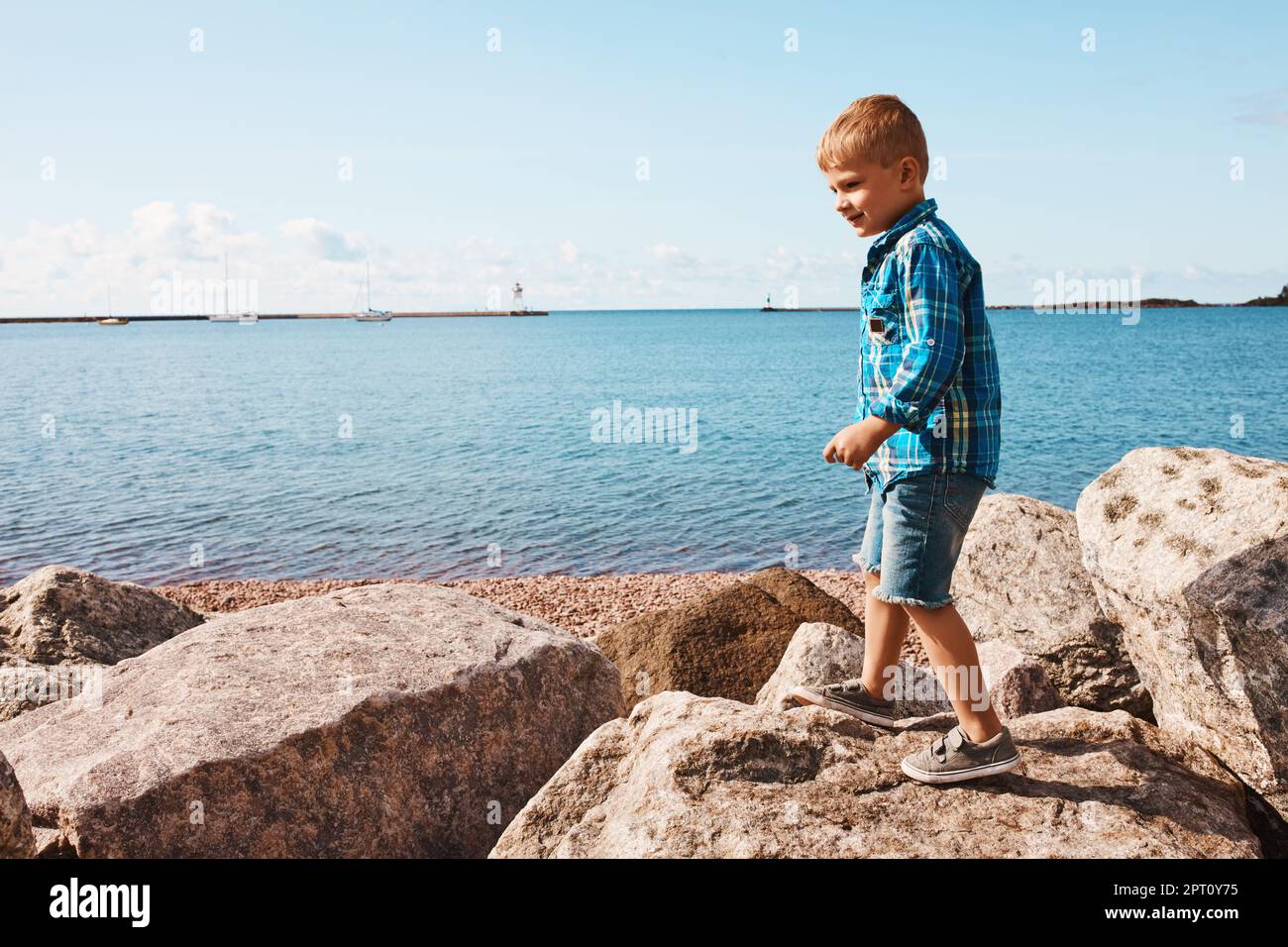 Playing on the rocky side. an adorable little boy playing on the rocks ...