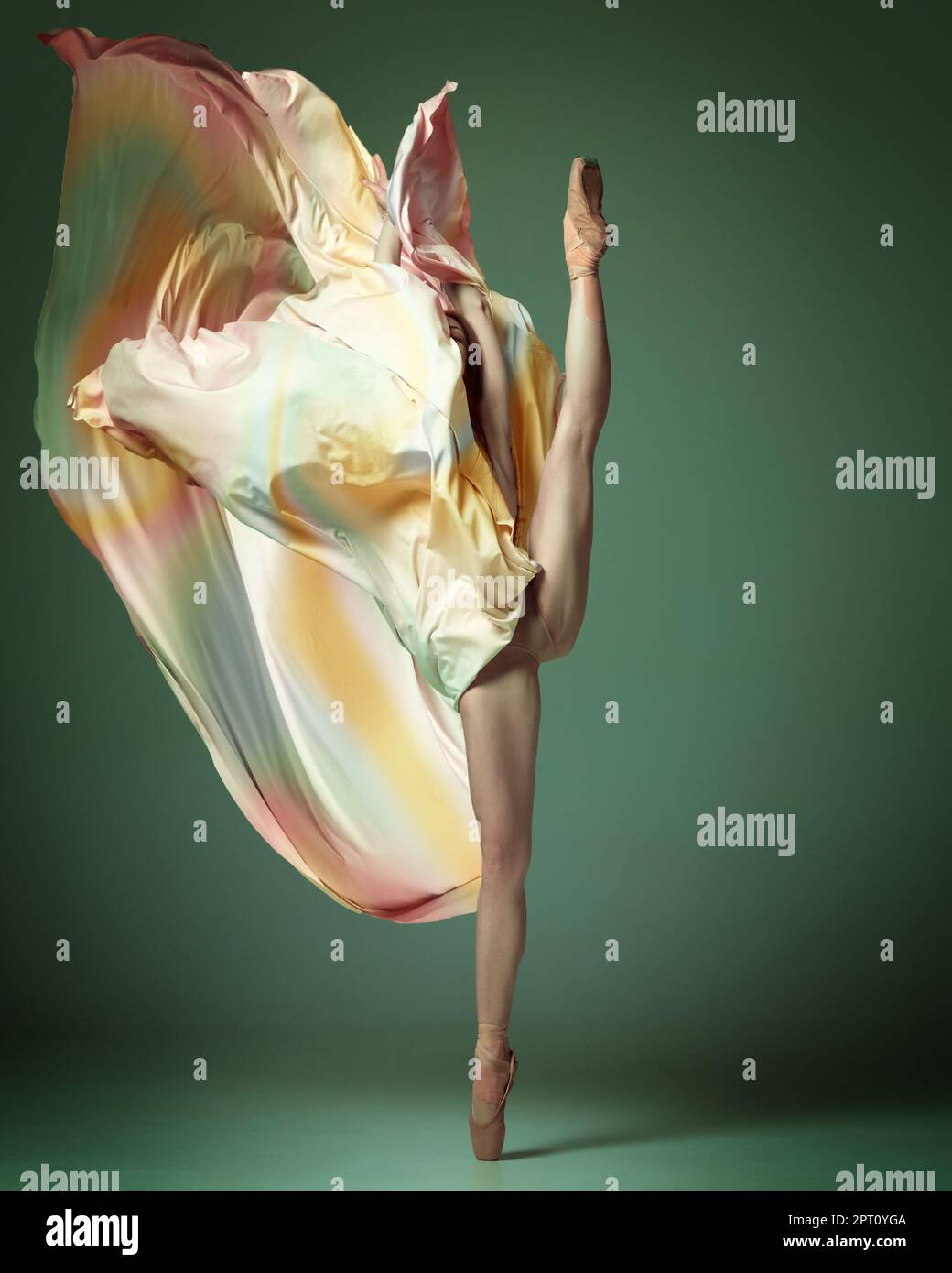 One young professional ballet dancer, girl wearing rainbow dress dancing over dark green studio ...