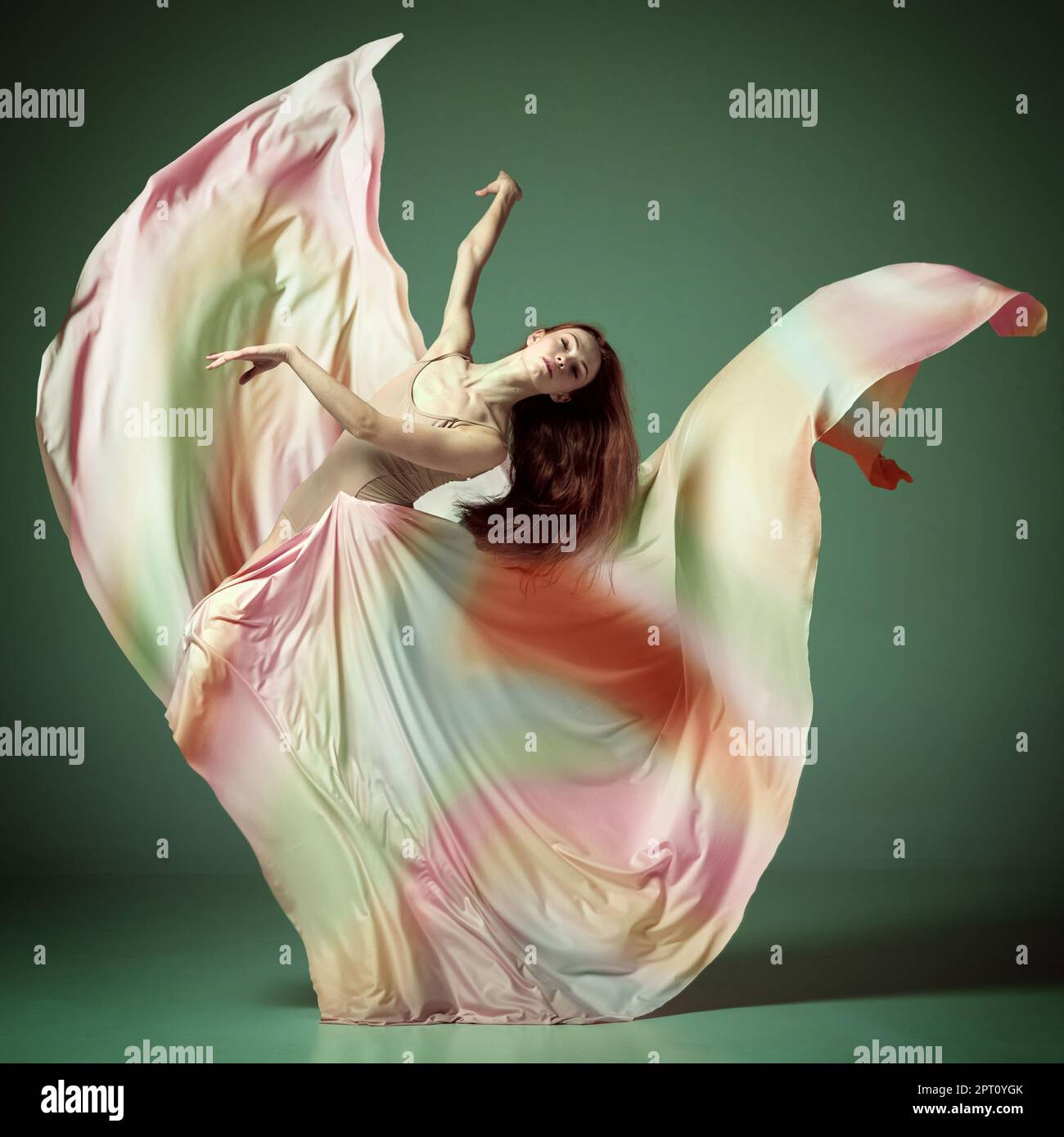 Portrait with one young girl, gorgeous ballerina wearing silk dress spinning in dance over dark ...