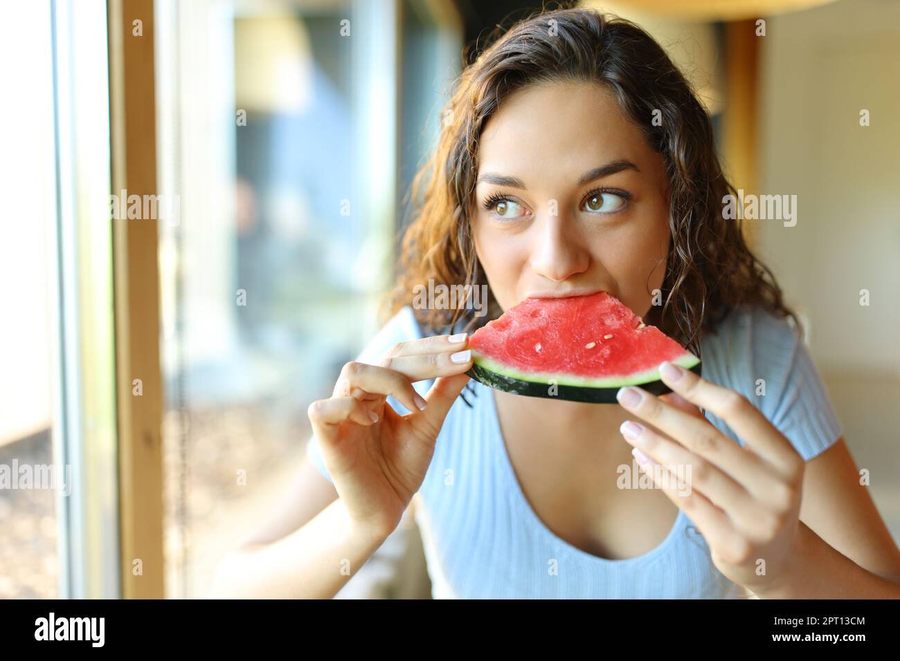 Woman in a restaurant eating watermelon looking through a window Stock ...