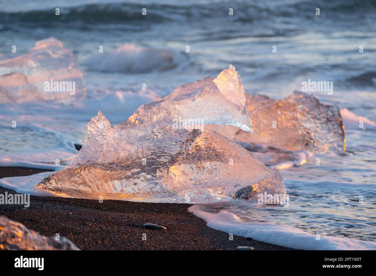 Pure Ice Shining on Black Volcanic Sand at Sunset. Icebergs from ...