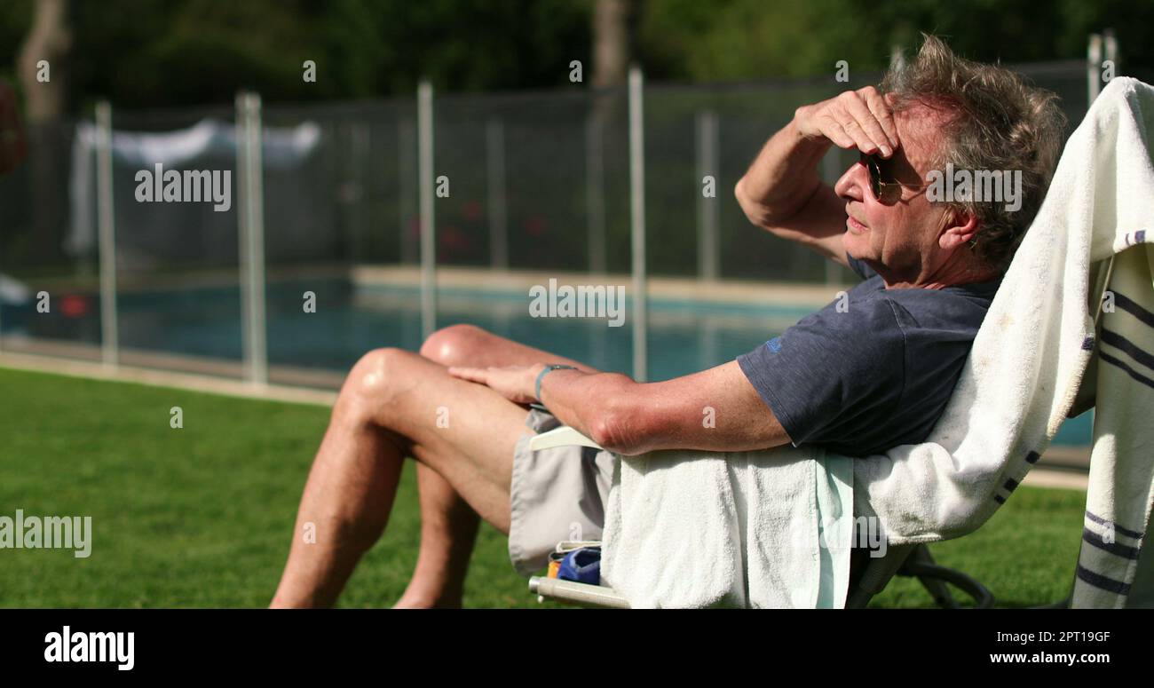 Senior retired man resting in outdoor home backyard covering face from ...