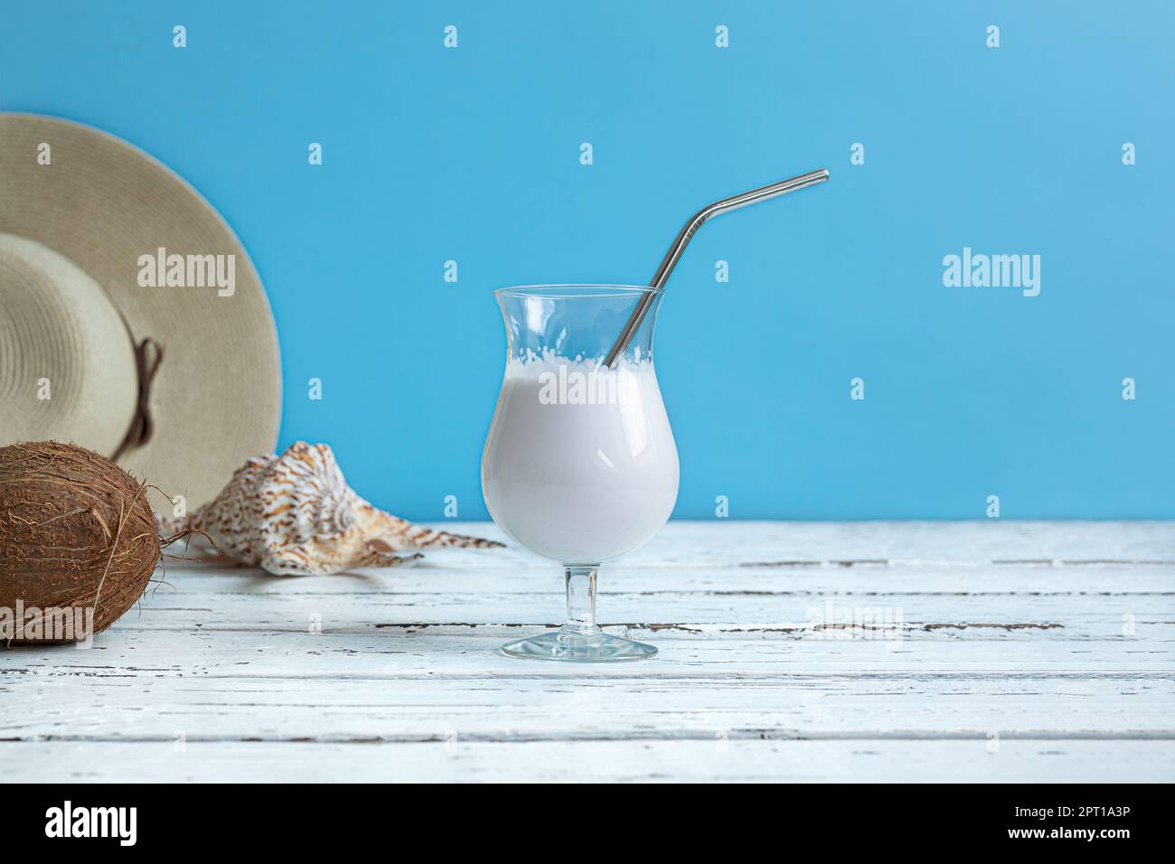 A glass of coconut milk cocktail with reusable metal cocktail tube, a ...