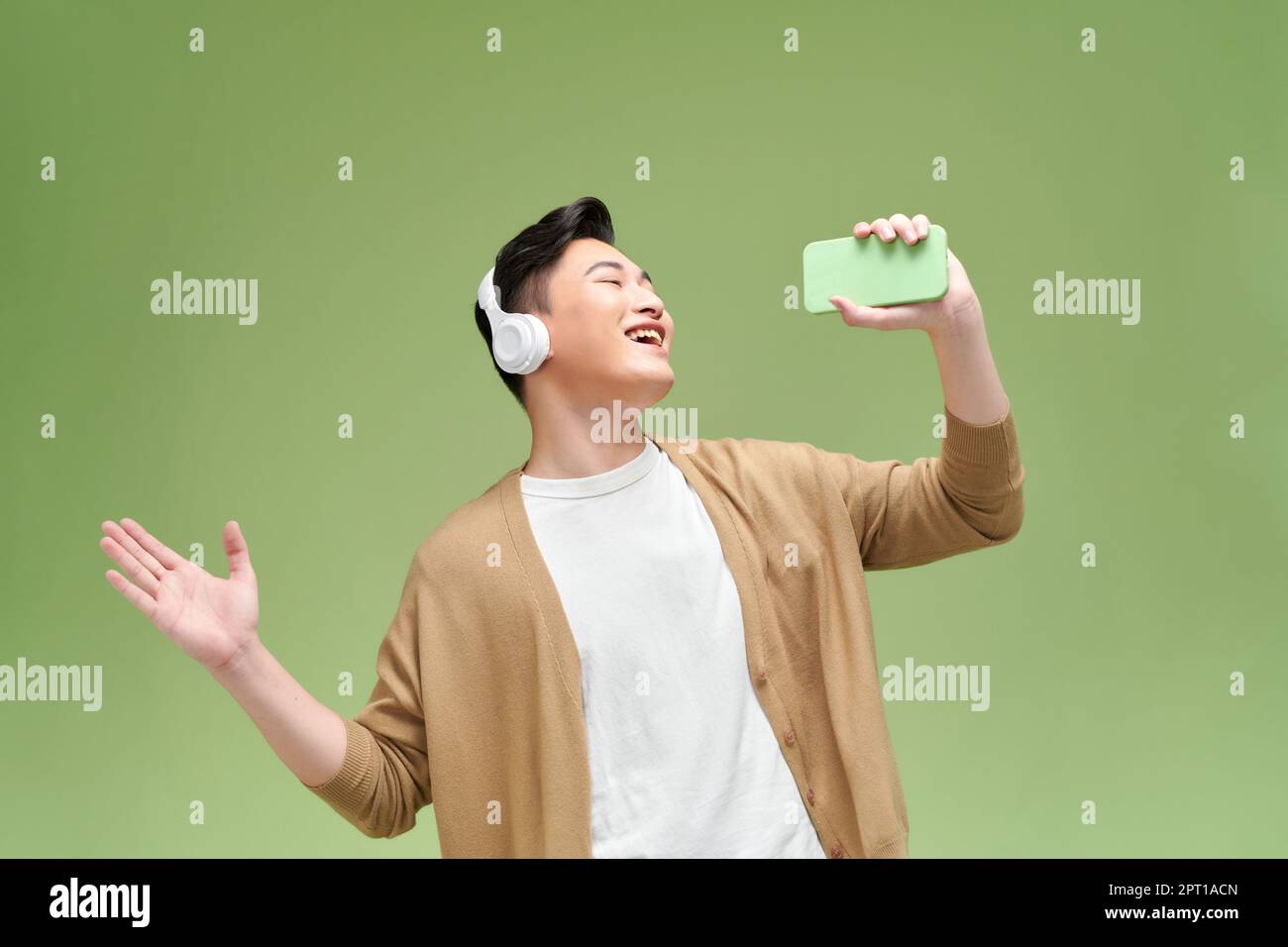 Emotional young man in headphones listening to music, singing song ...
