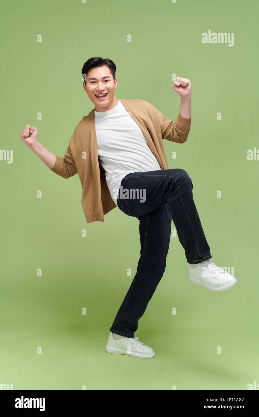 Happy excited young Asian man jumping isolated on green studio ...
