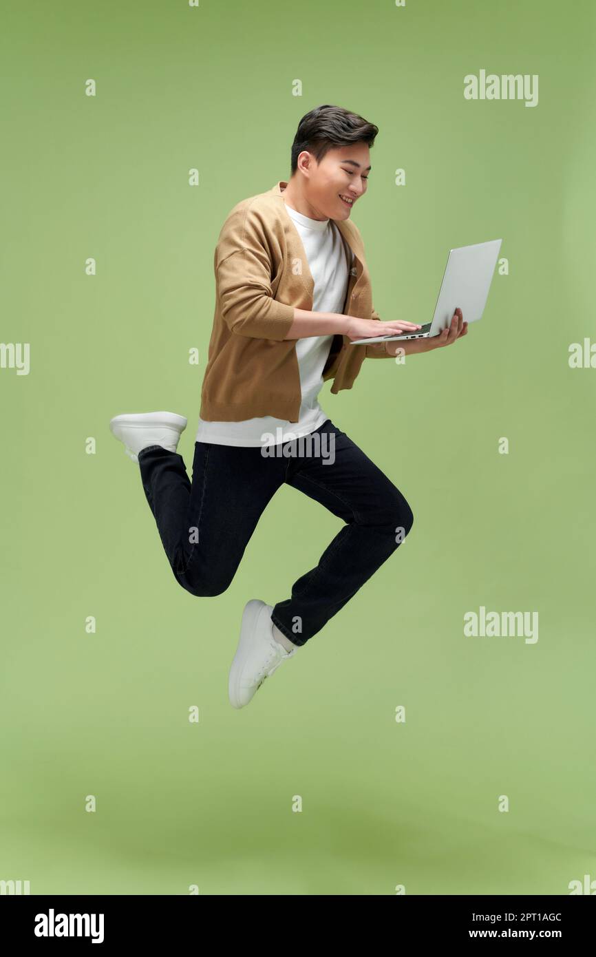 Full length photo of positive man jumping high holding device isolated ...