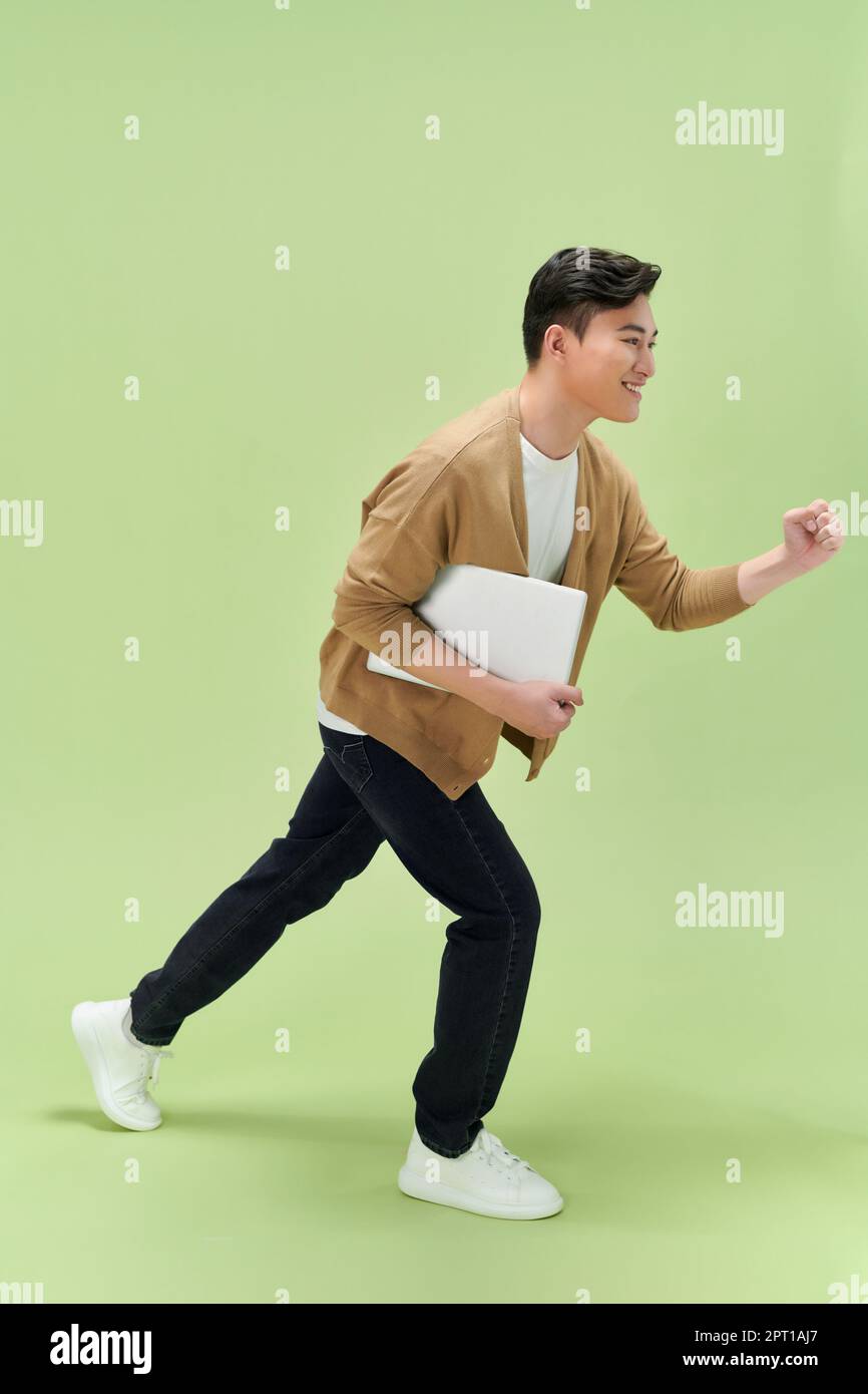 positive businessman running busily and holding a laptop Stock Photo ...