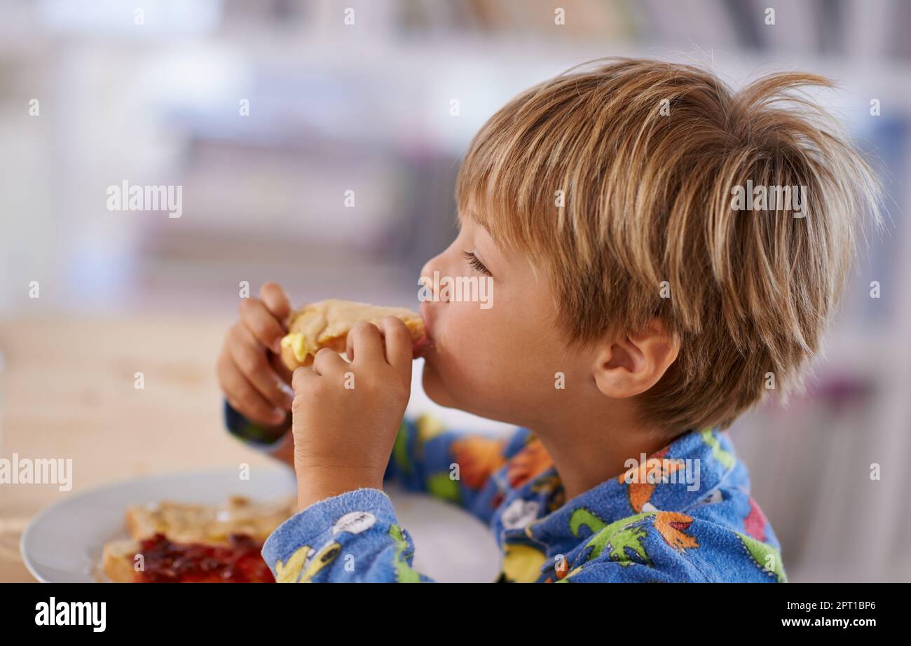 Great way to start the day. A cute little boy eating toast with peanut ...