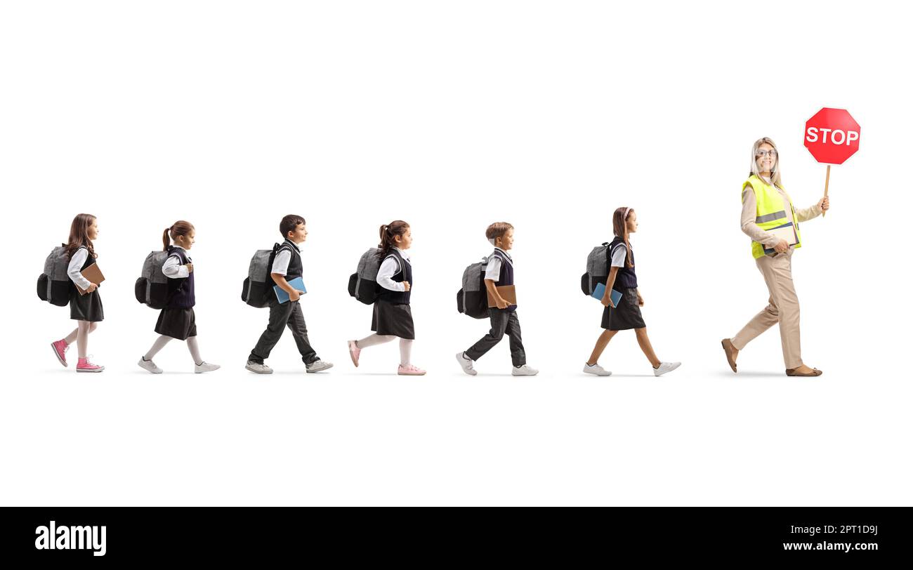 Full length profile shot of schoolchildren walking behind a teacher ...