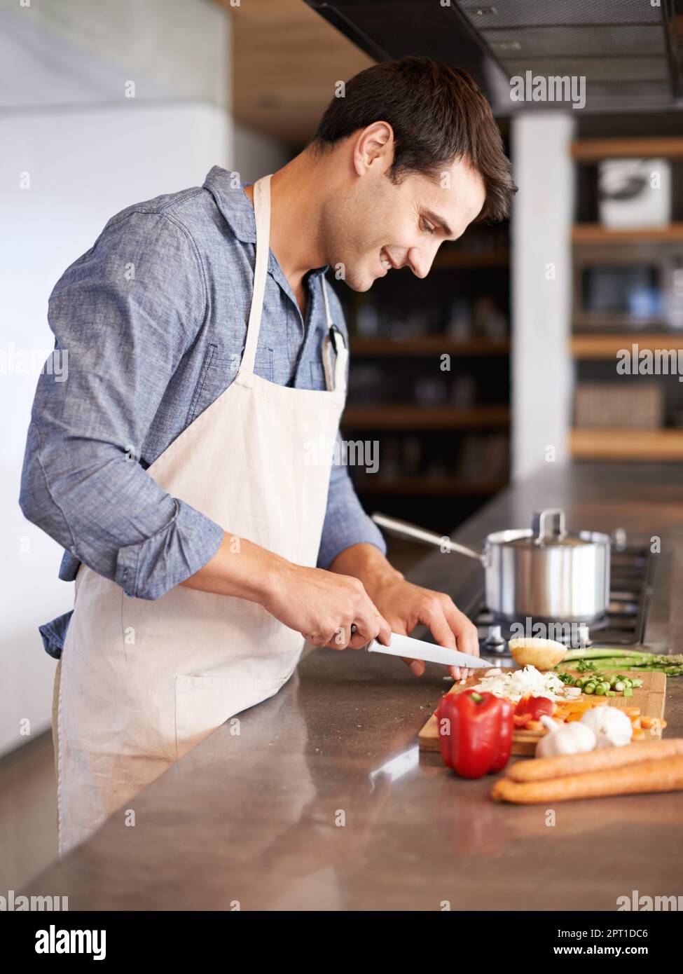Real men cook. a handsome young man chopping vegetables in his kitchen ...