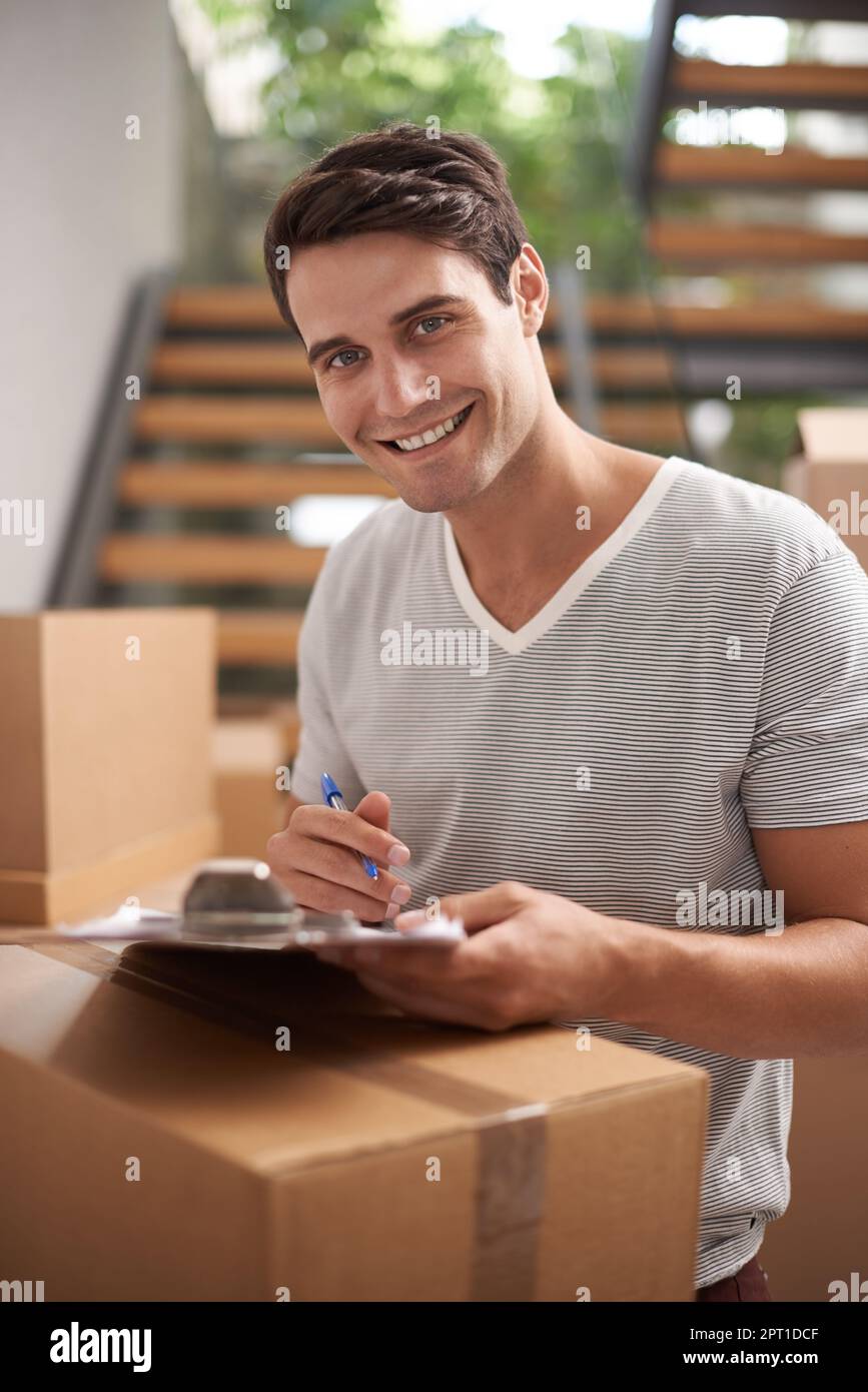 Time to move in. A happy young man signing for a delivery of packed ...