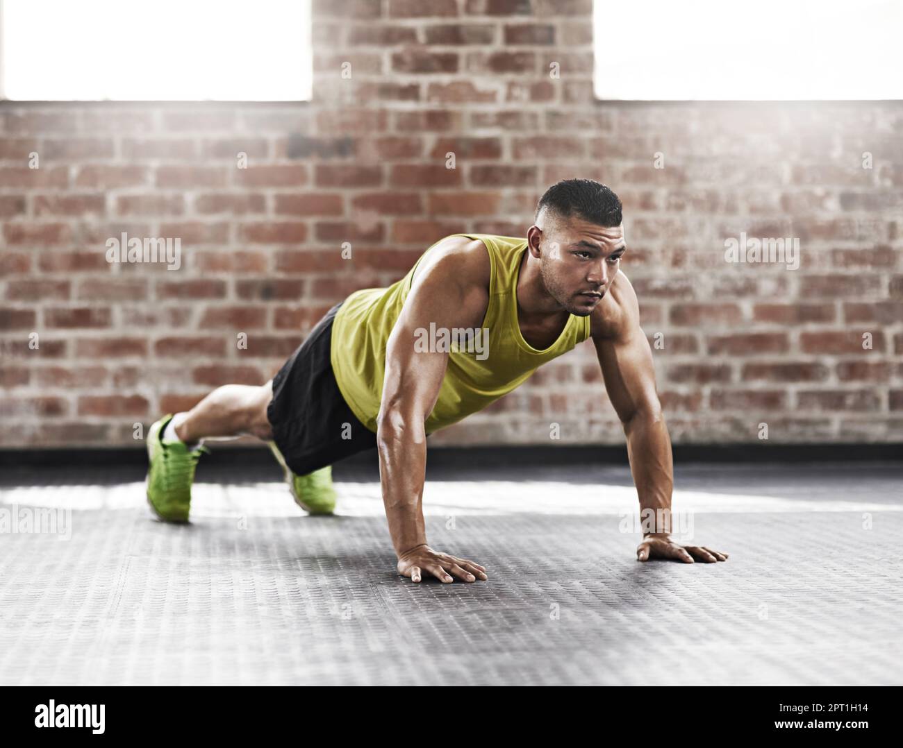 Pushing past his limits. Full length shot of a young man working out in ...