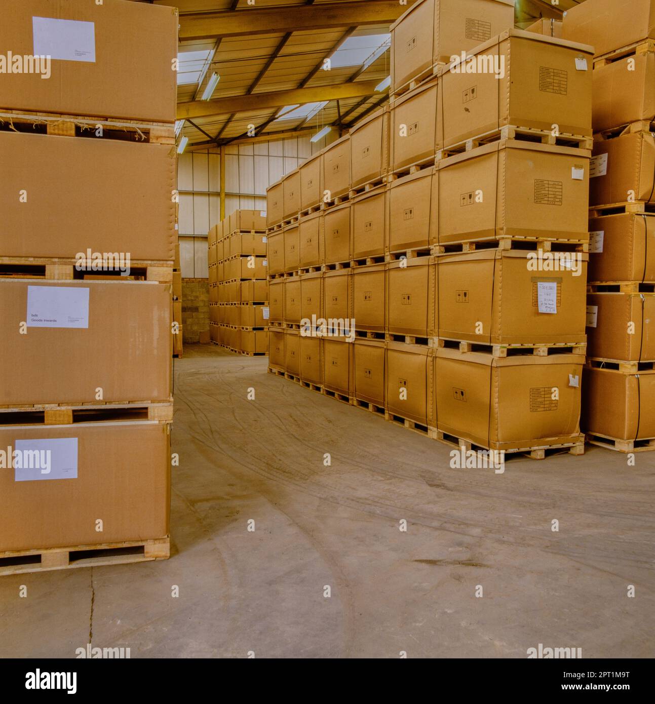 Wooden pallets and cardboard boxes stacked in distribution warehouse ...