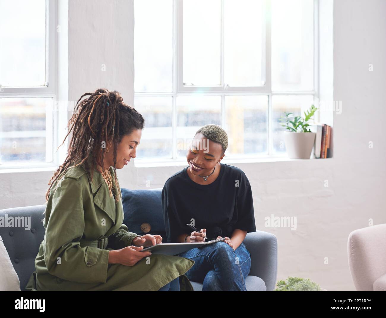 African american woman writing notes with friend showing ideas on ...