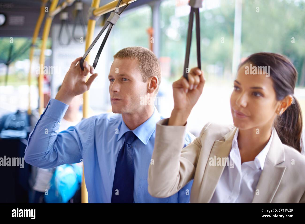 Commuting colleagues. Two businesspeople riding the bus on their way to ...