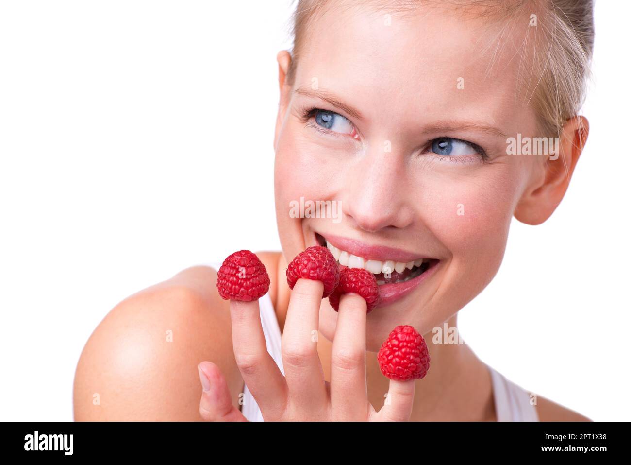 Natures play food. a beautiful young woman playfully eating raspberries ...