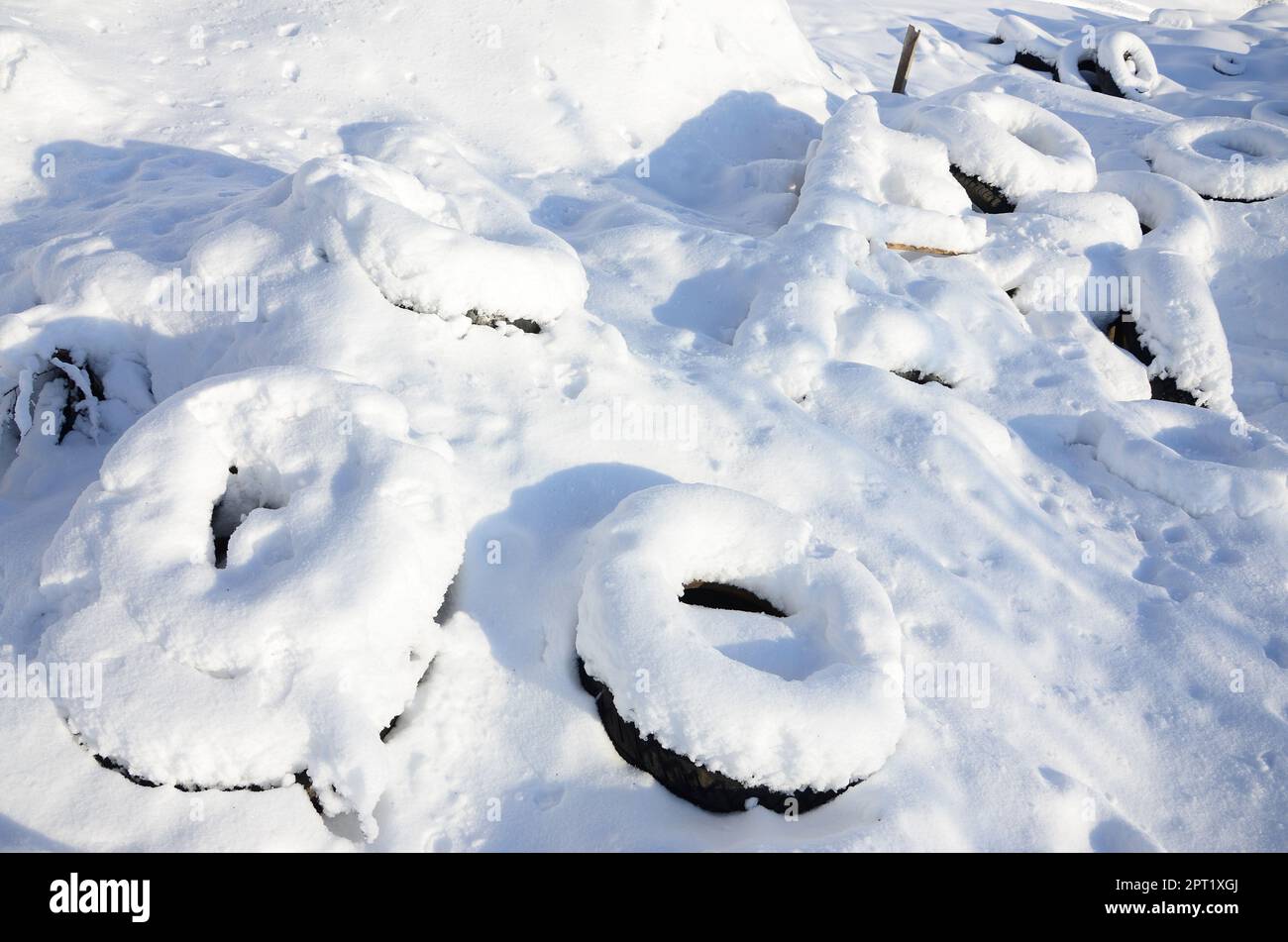 Used and discarded car tires lie on the side of the road, covered with a thick layer of snow ...