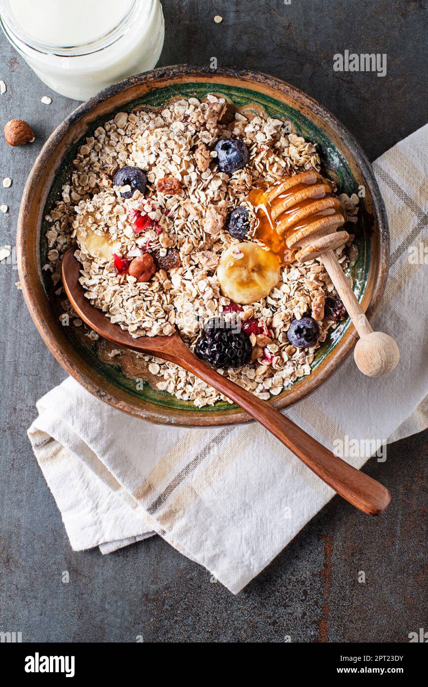 A bowl of dry granola and muesli served with fresh fruit nuts and honey ...