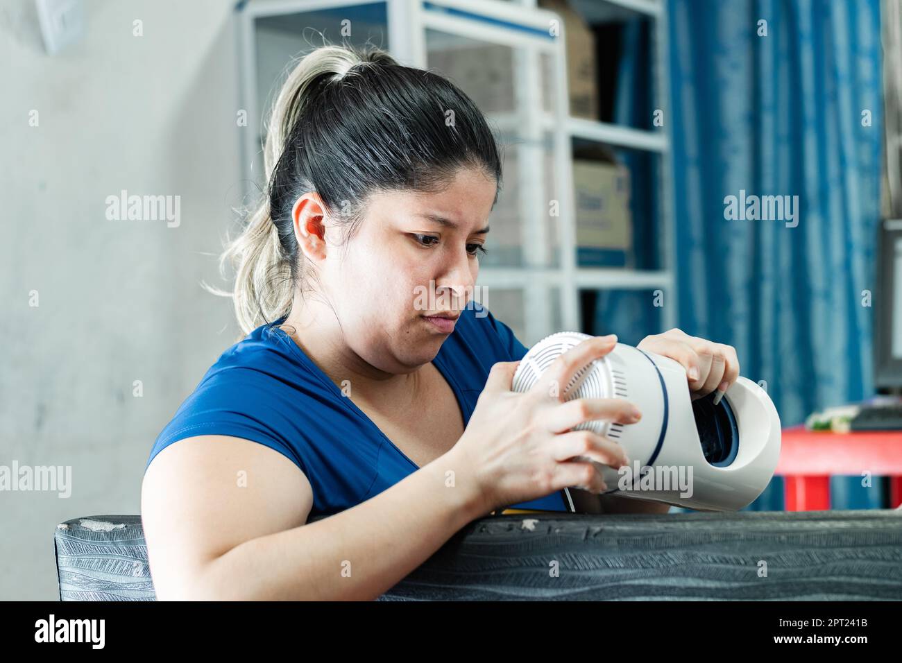 young latina woman very confused trying to disassemble a broken ...