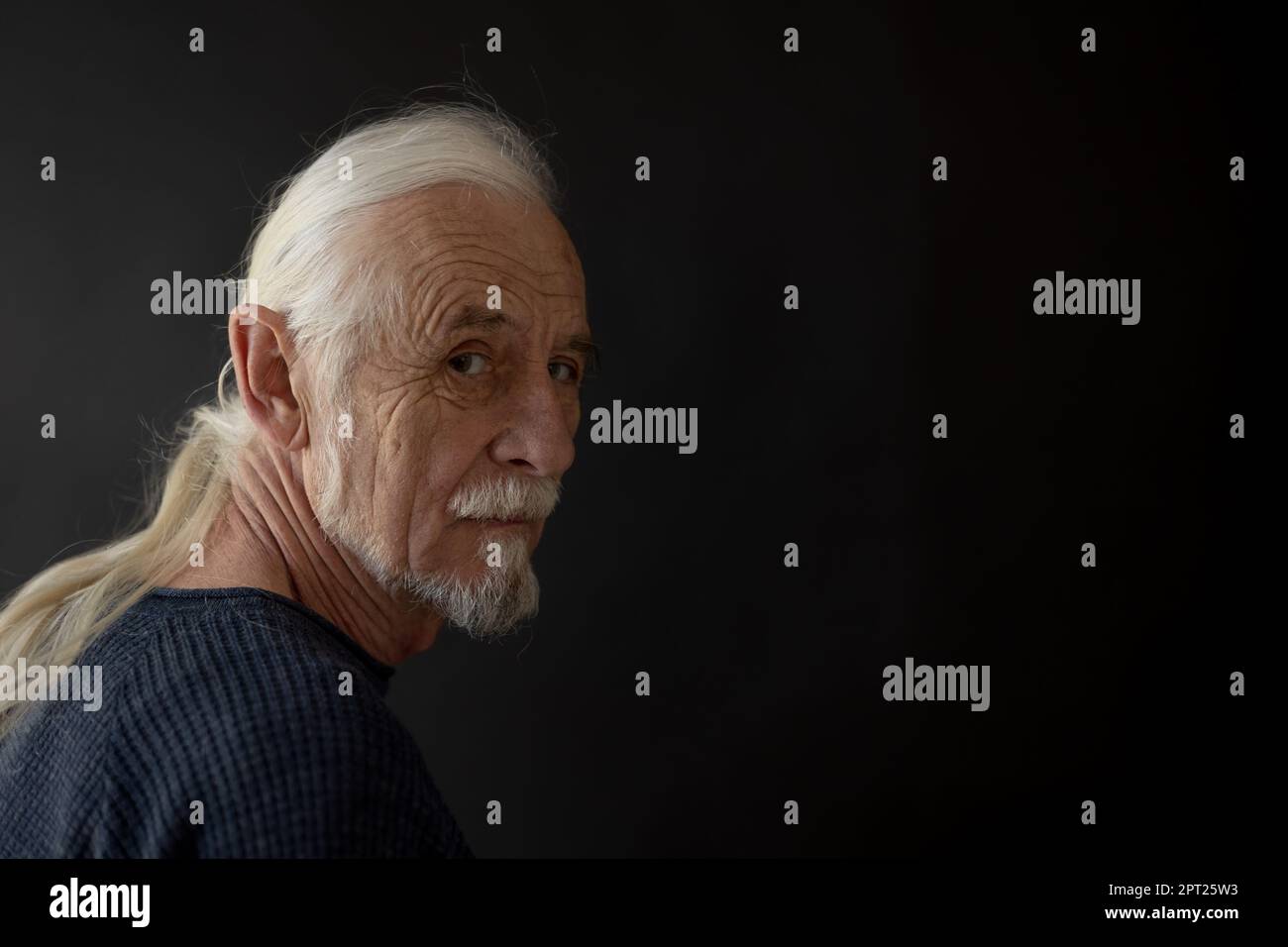 Low key studio portrait of beautiful old man with gray hair in a braid ...