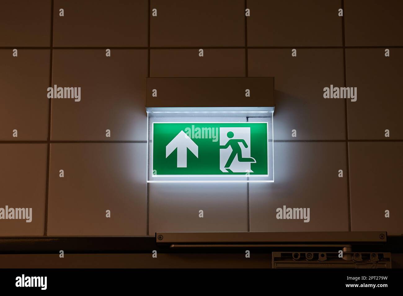 Emergency exit sign glowing in the dark Stock Photo - Alamy