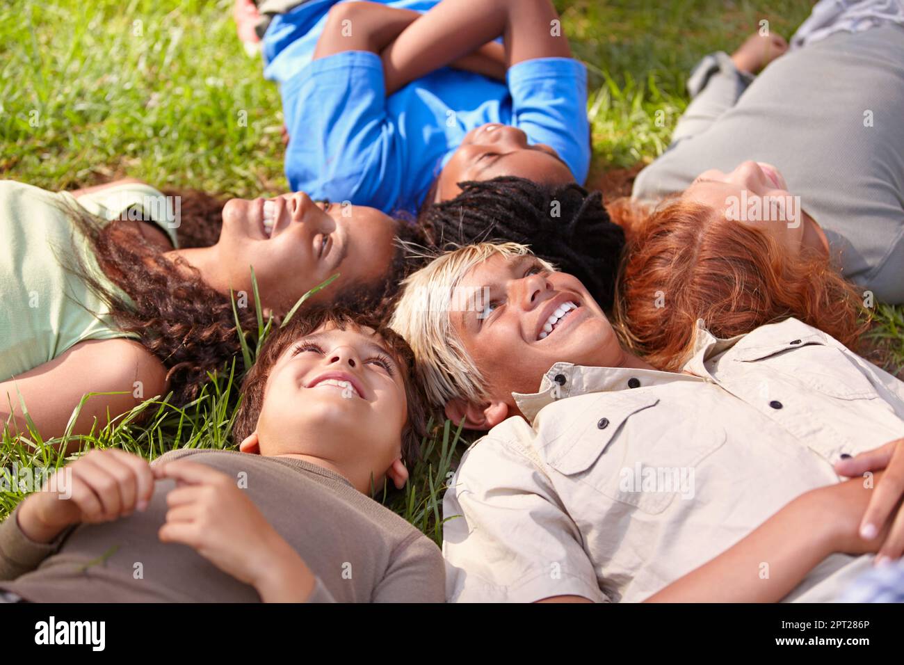 Finding faces in the clouds. a young kids lying in the grass together ...
