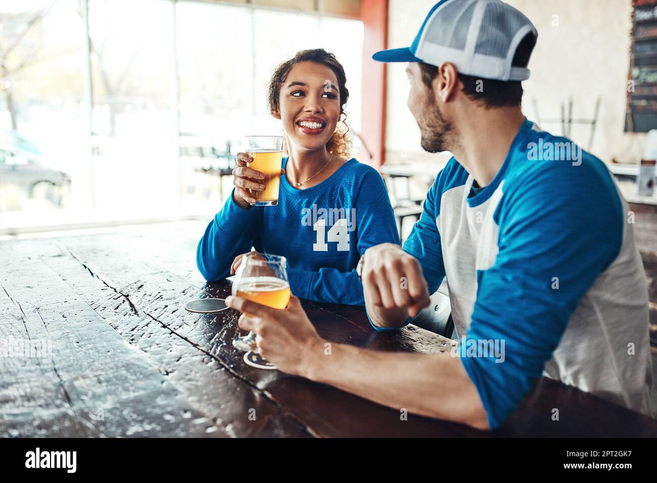 Sporty couple kind of dates. a young man and woman having beers while ...
