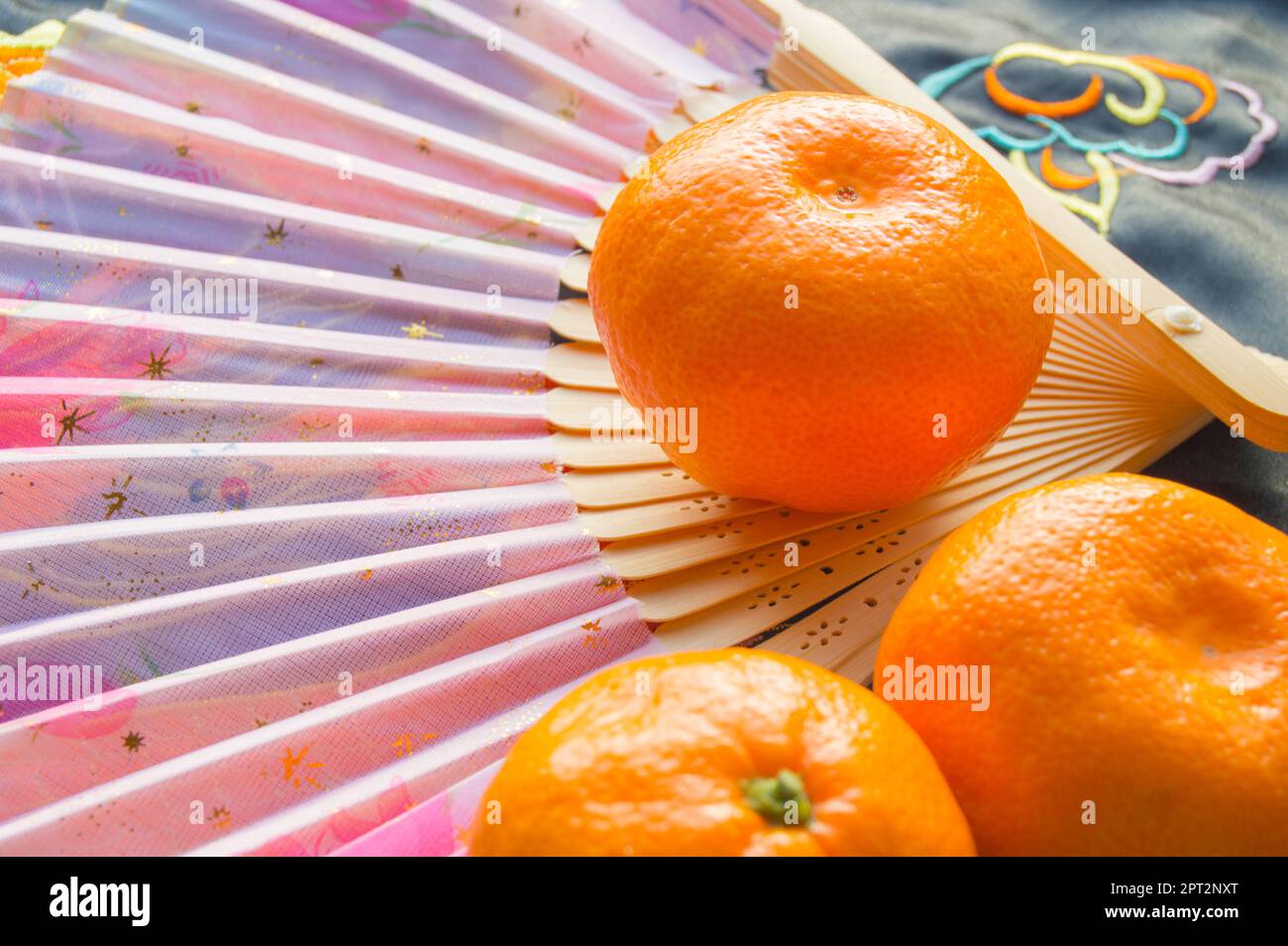 Chinese New year, tangerines and a fan lying on the silk fabric with an ...
