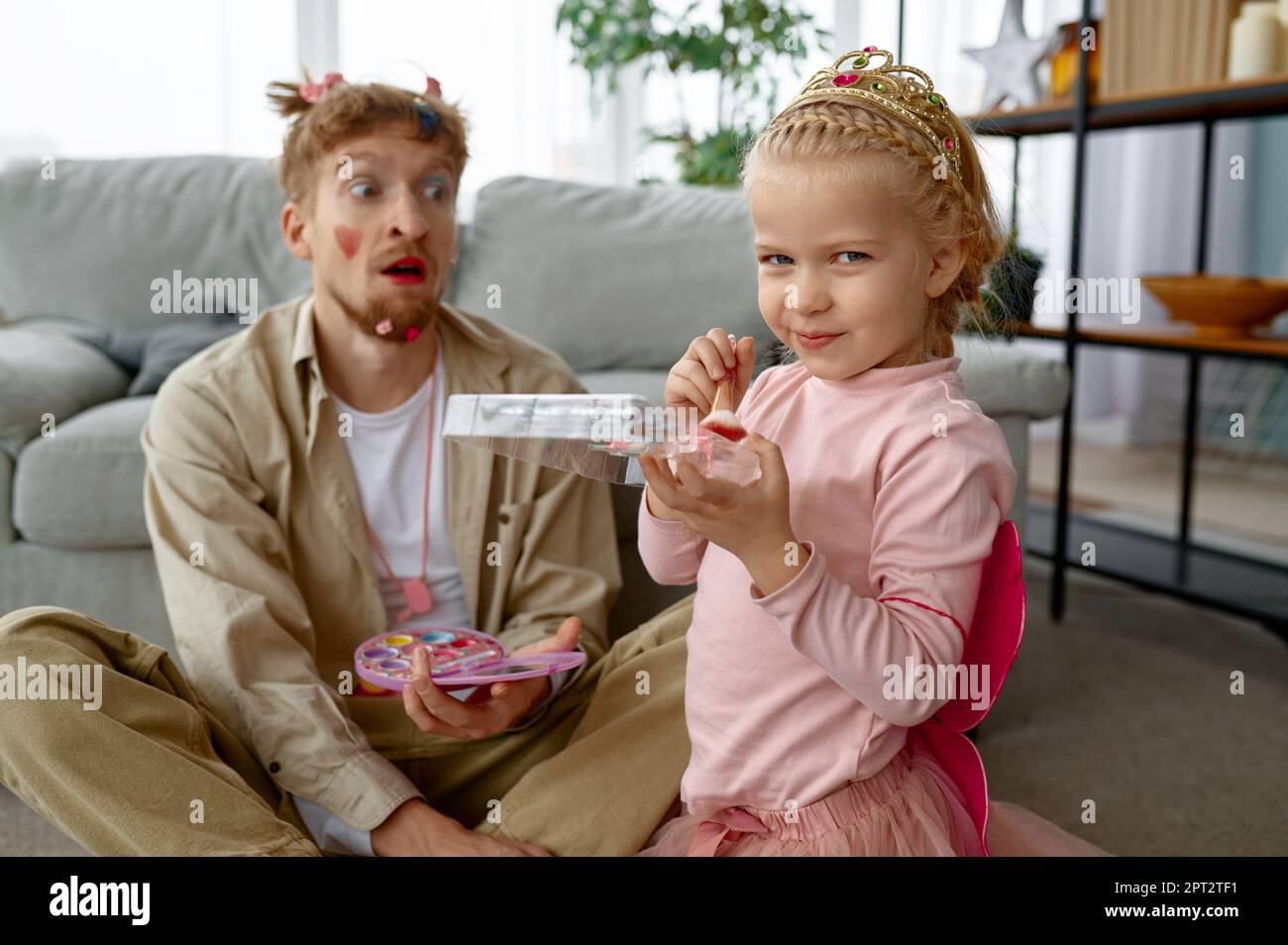Father with funny makeup and hairstyle spends time with daughter, focus ...