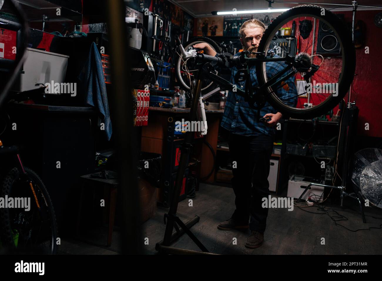 Wide shot of cycling mechanic male watching rear shifter of mountain ...