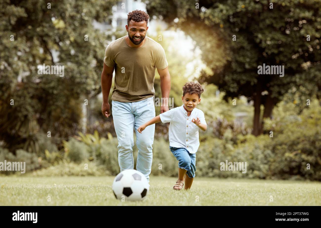 Father, child and playing with soccer ball in the park for fun quality bonding time together in ...