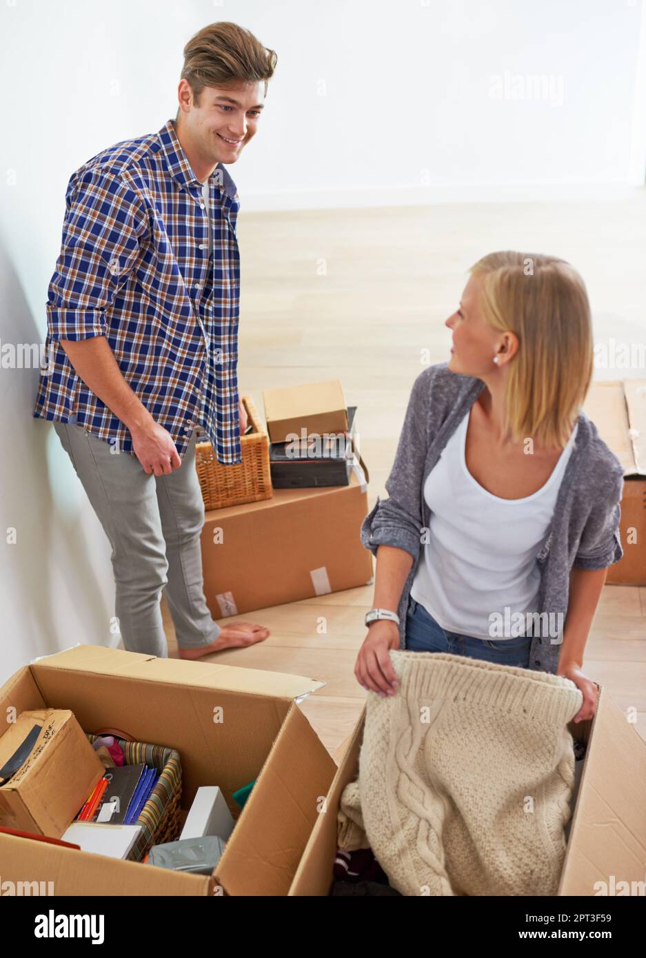 We finally made the move. A young couple unpacking boxes in their new apartment after making the ...