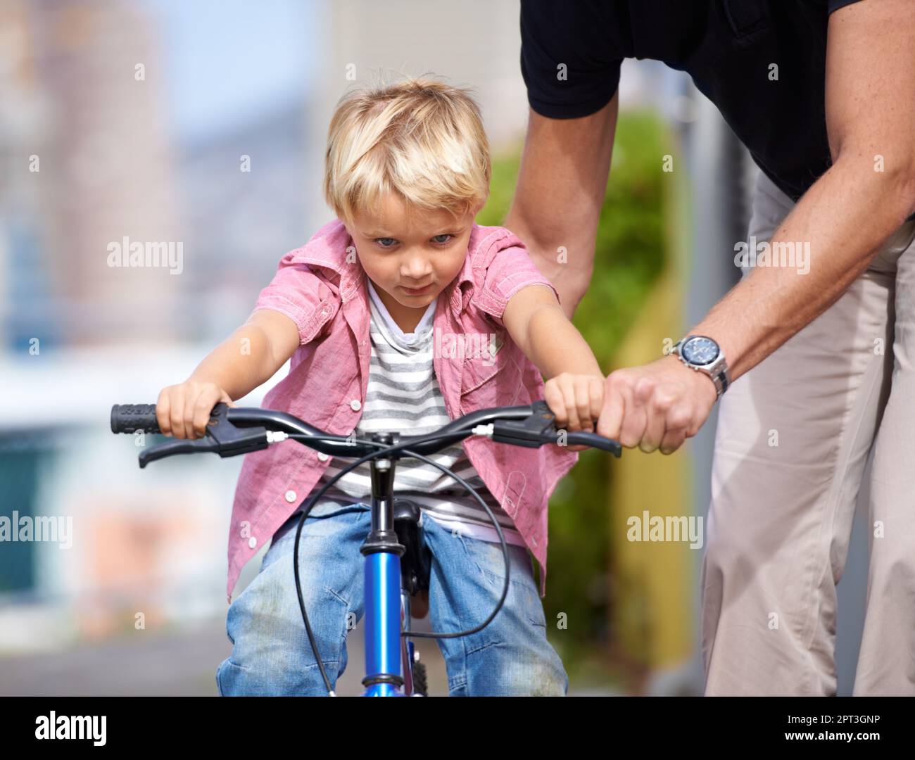 Hell be riding on his own soon. A father teaching his young son to ride a bike Stock Photo - Alamy