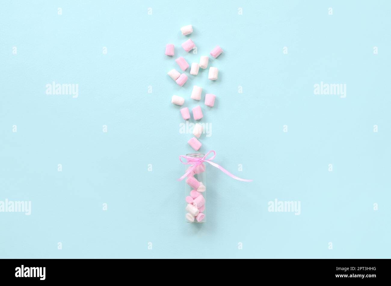 Pink and white marshmallow pieces is sprayed from a small glass ...