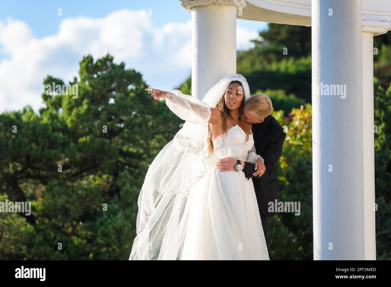 The groom kisses the neck of the bride, the bride shows her hand into ...