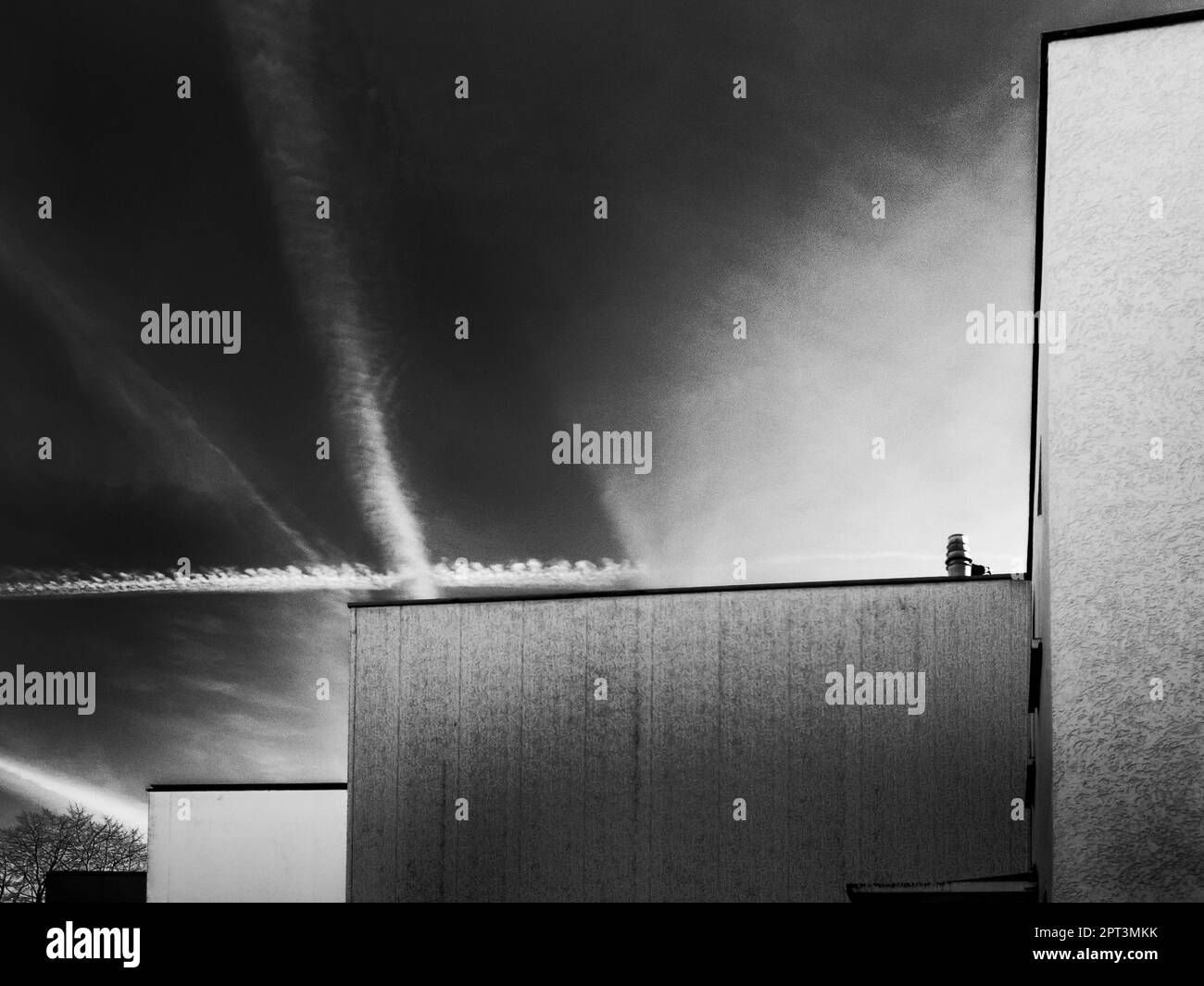 Architectural view with row house roof edges in front of a cloudless sky angled with contrails ...