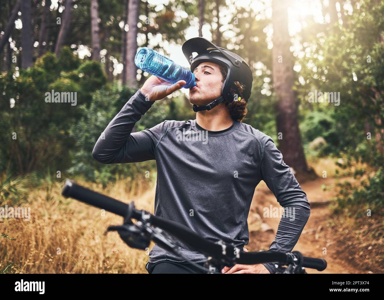 Mountain bike man drinking water bottle in forest, woods and mountains ...