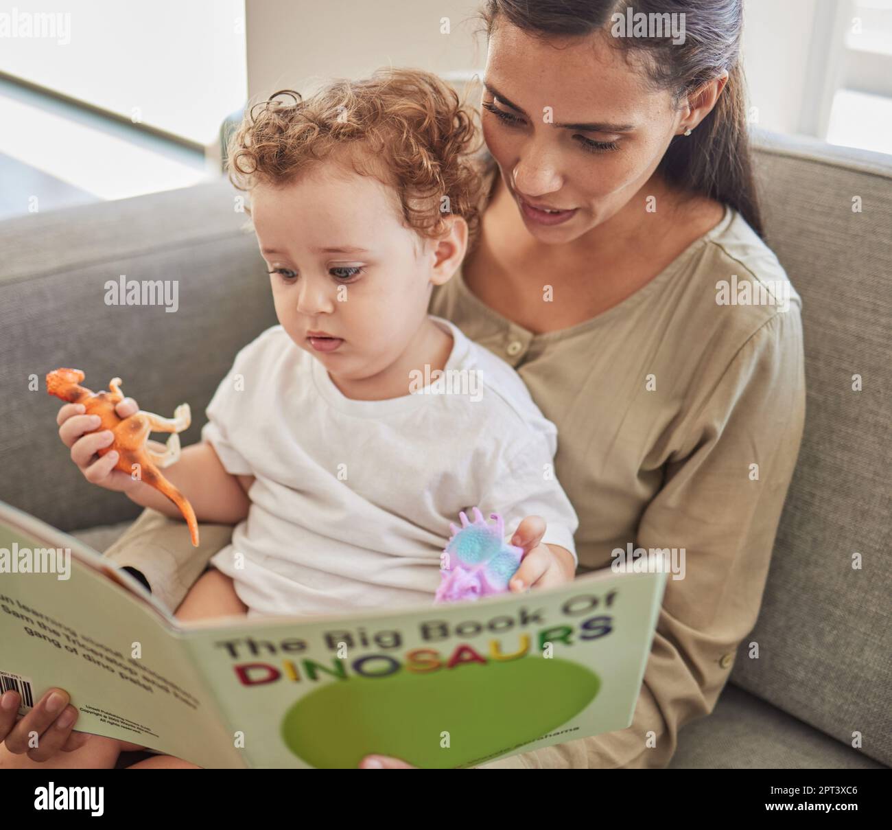 Family, baby and reading a book with a mother and boy child on a sofa ...