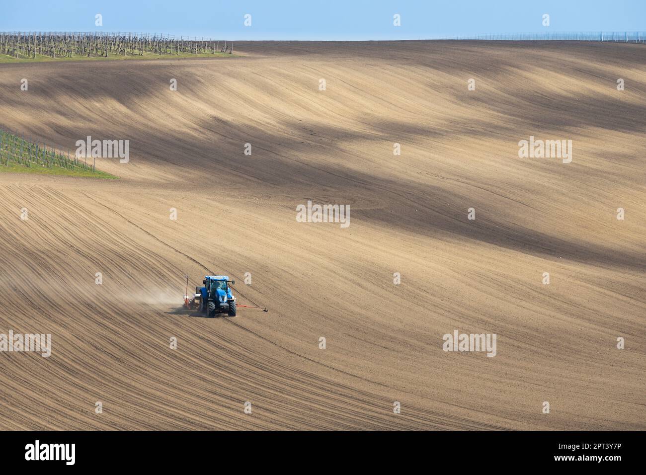 Tractor with seed drill in early spring landscape Stock Photo - Alamy