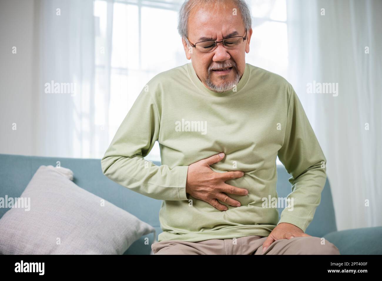 Elderly Asian old man sitting on sofa having stomachache, old age ...