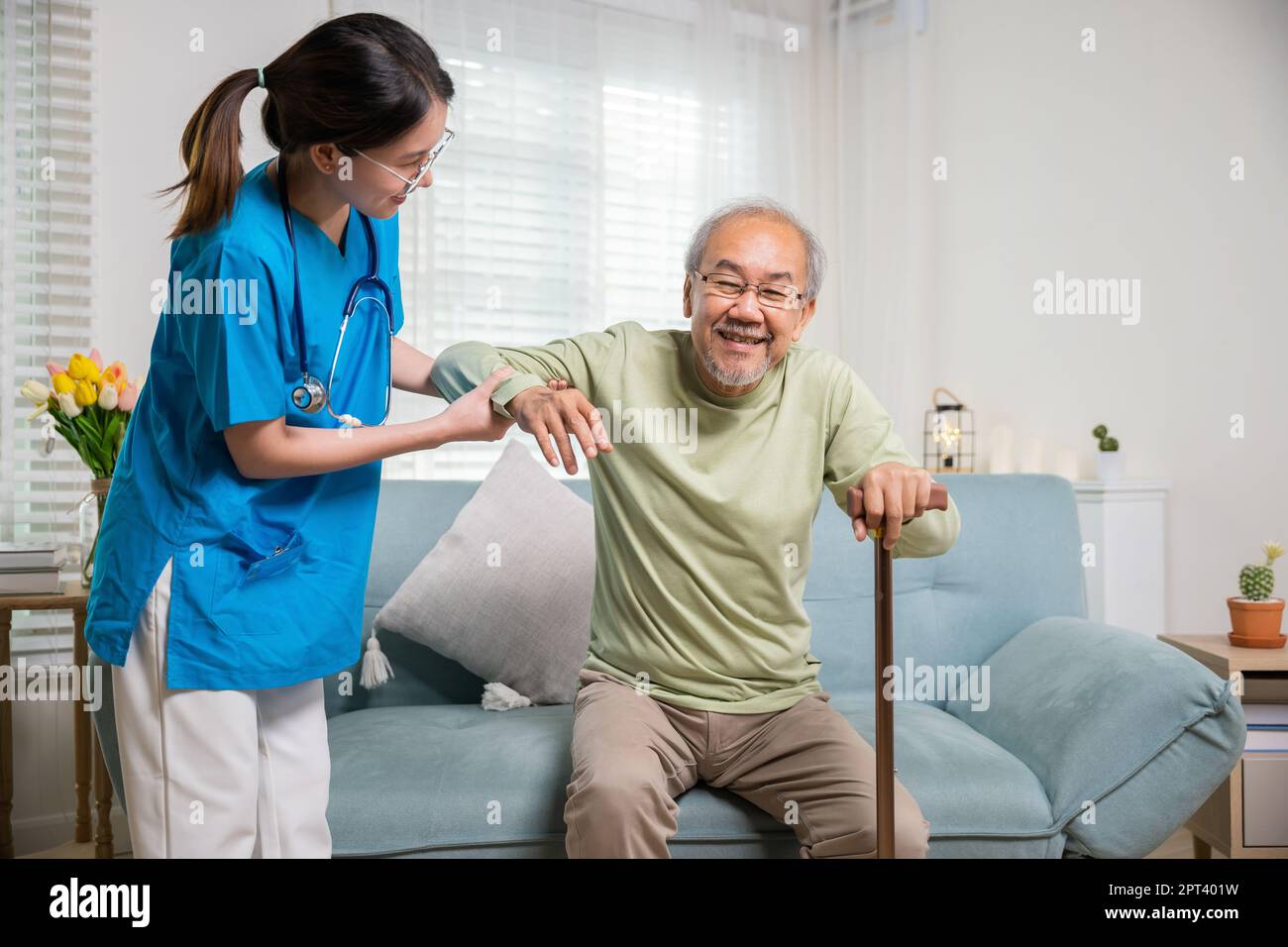 International Day for the Elderly. Young carer supporting helping senior man stand up with ...