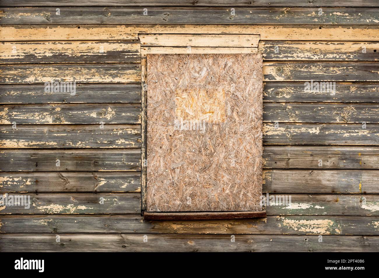 An old wooden window boarded up with plywood on a wooden wall. Easy way ...