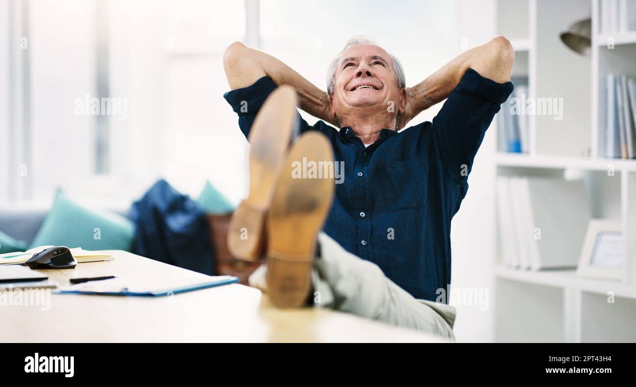 Thats enough work for the day. a cheerful mature businessman lying back ...