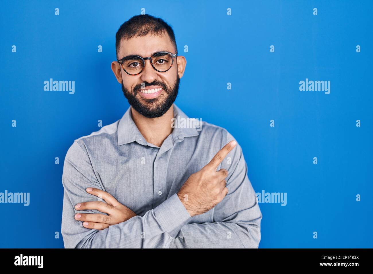 Middle east man with beard standing over blue background with a big ...