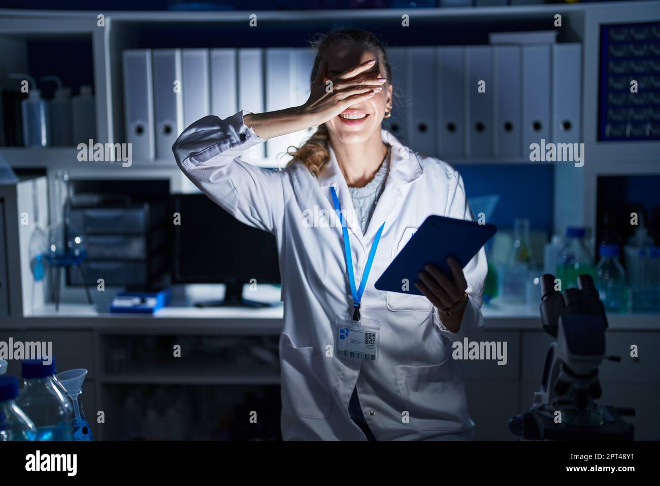 Beautiful blonde woman working at scientist laboratory late at night ...