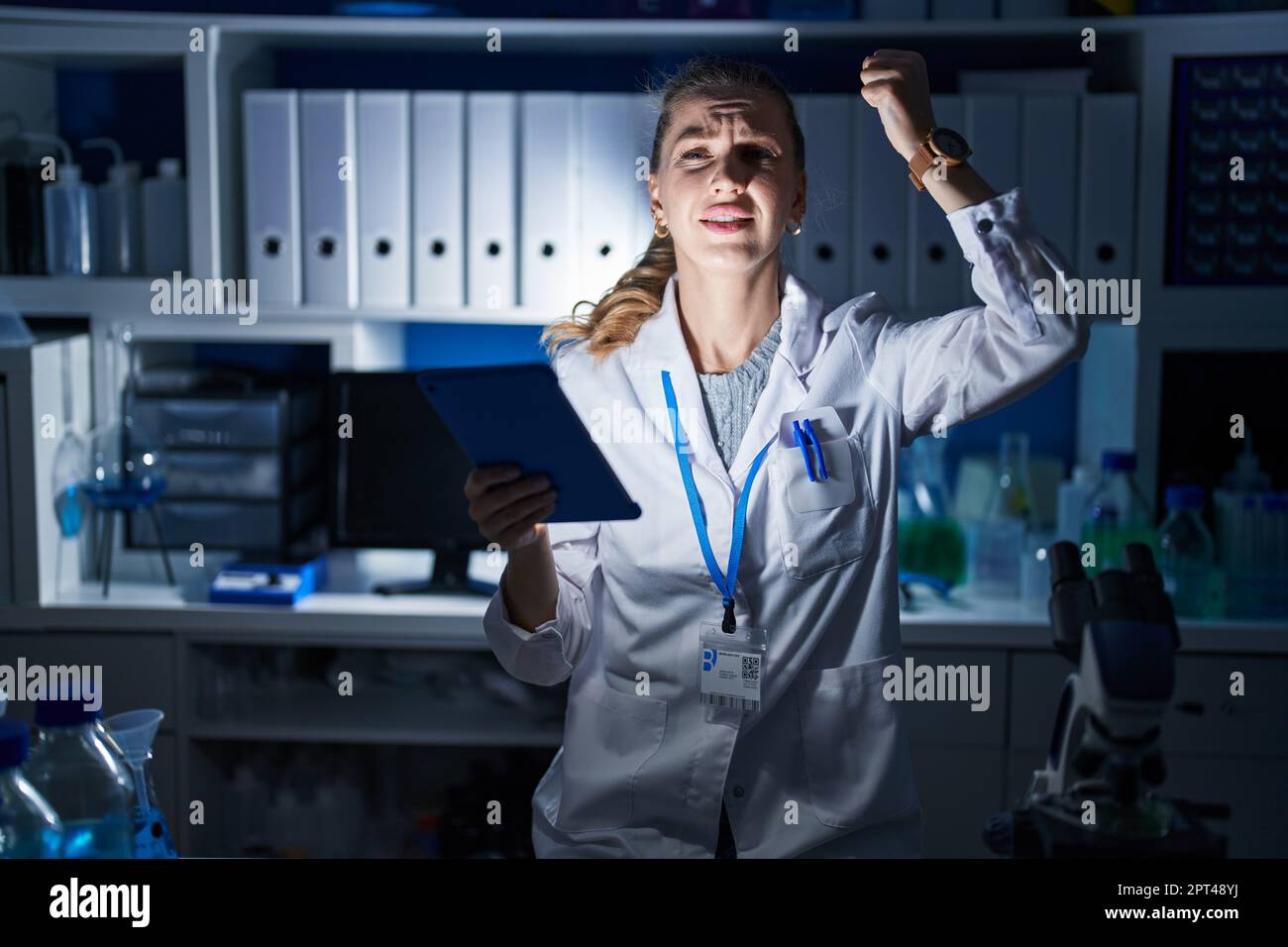 Beautiful blonde woman working at scientist laboratory late at night ...