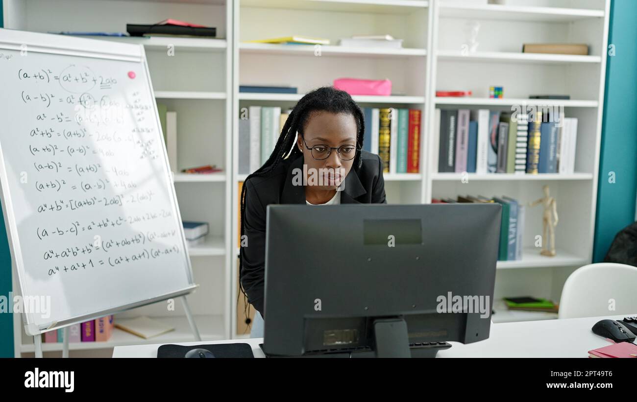 African american woman teacher teaching maths lesson using computer at ...