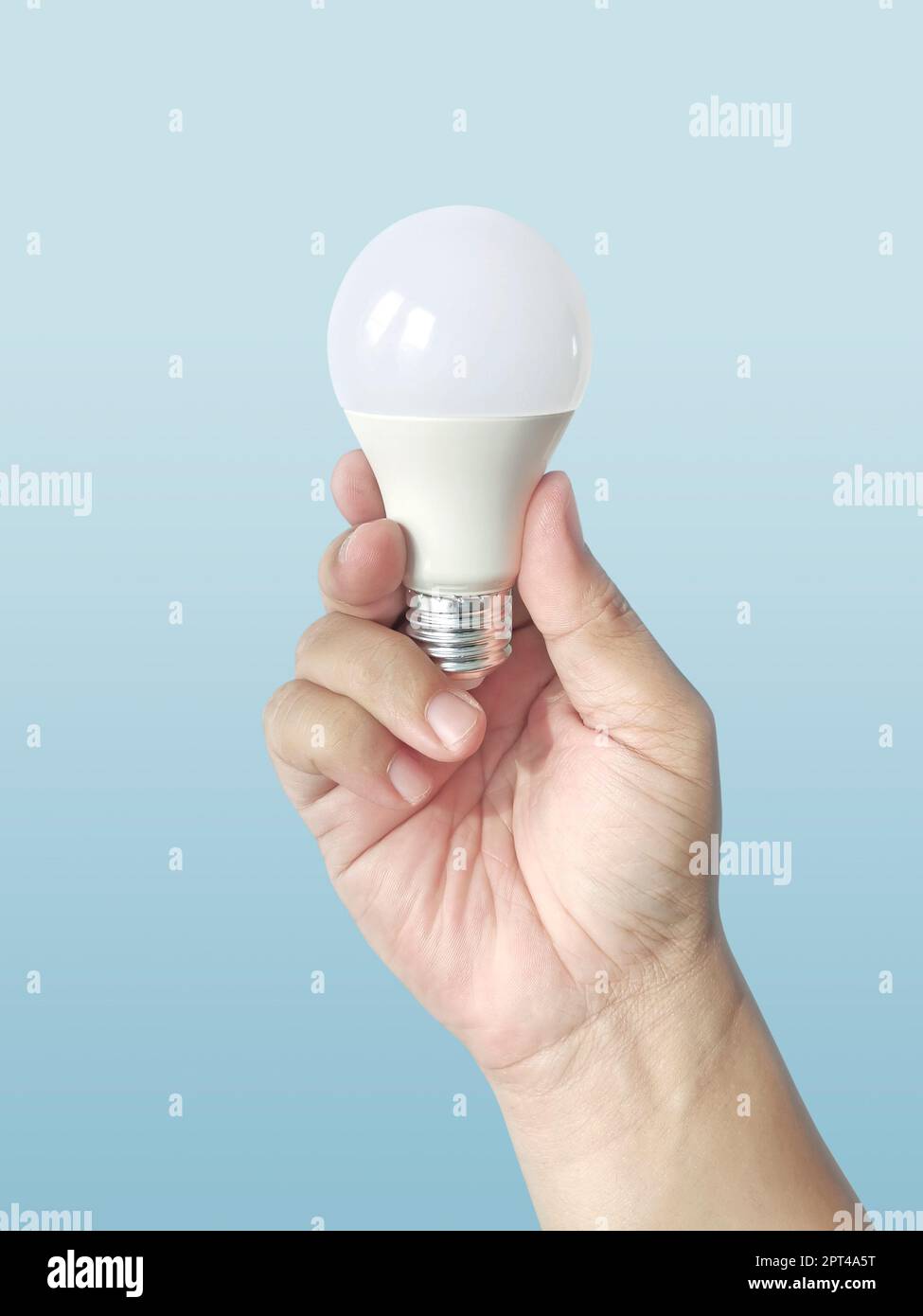 Hand holding a LED light bulb on blue background. Using economical and ...