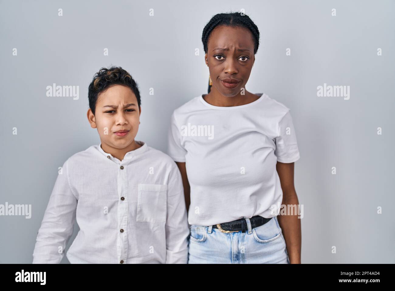Young mother and son standing together over white background depressed ...