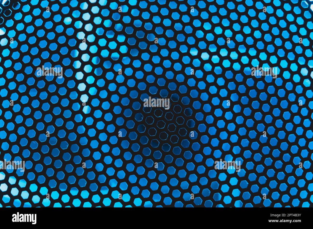 Blue light shines through the ventilation grid holes of computer air ...